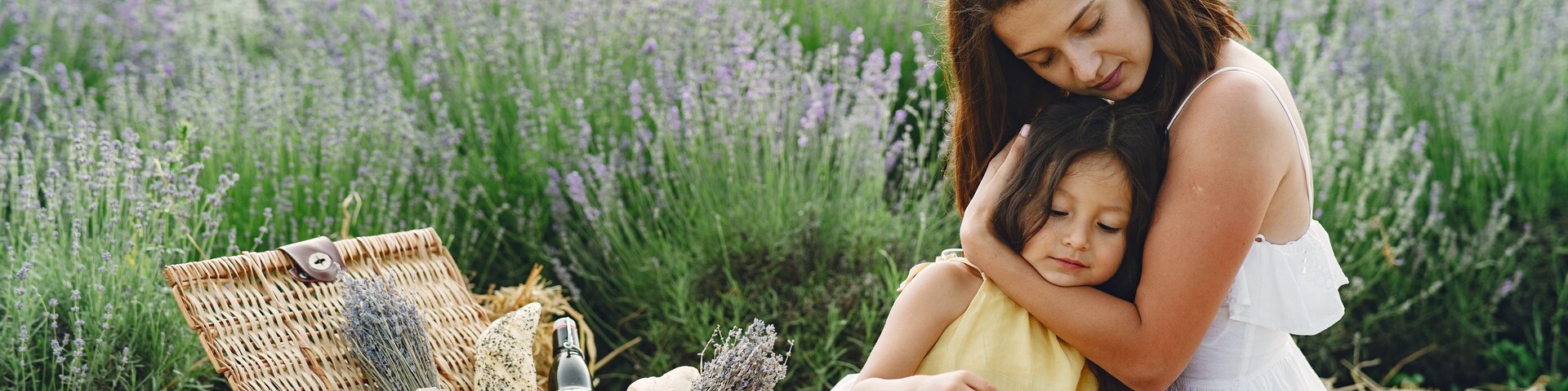 Piquenique com cesta, coberta e comida em um campo de lavanda.