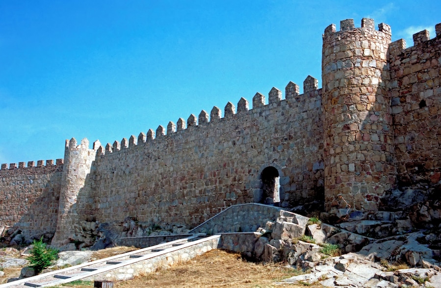 Um castelo de pedra com uma muralha alta e uma torre imponente.