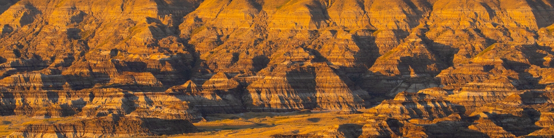 Vasta paisagem com formações rochosas sobrepostas e um campo plano em primeiro plano.