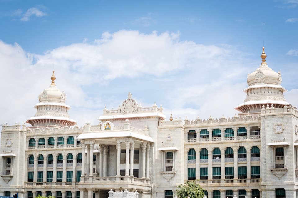 Um edifício branco imponente, com cúpulas ornamentadas e colunas.