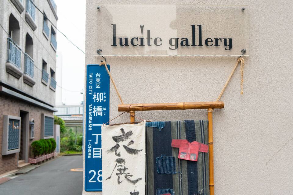 Placa da Lucite Gallery, com estrutura de bambu e uma placa azul com caracteres japoneses.