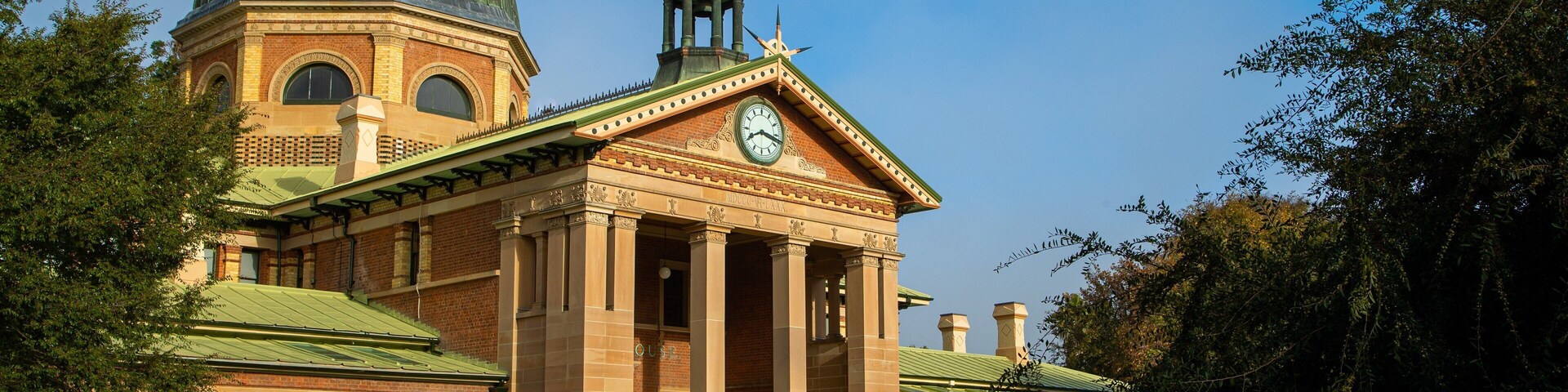 Um edifício grande e histórico com uma cúpula verde e torre do relógio.