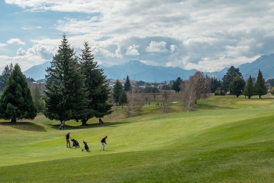 Um campo de golfe com montanhas ao fundo.