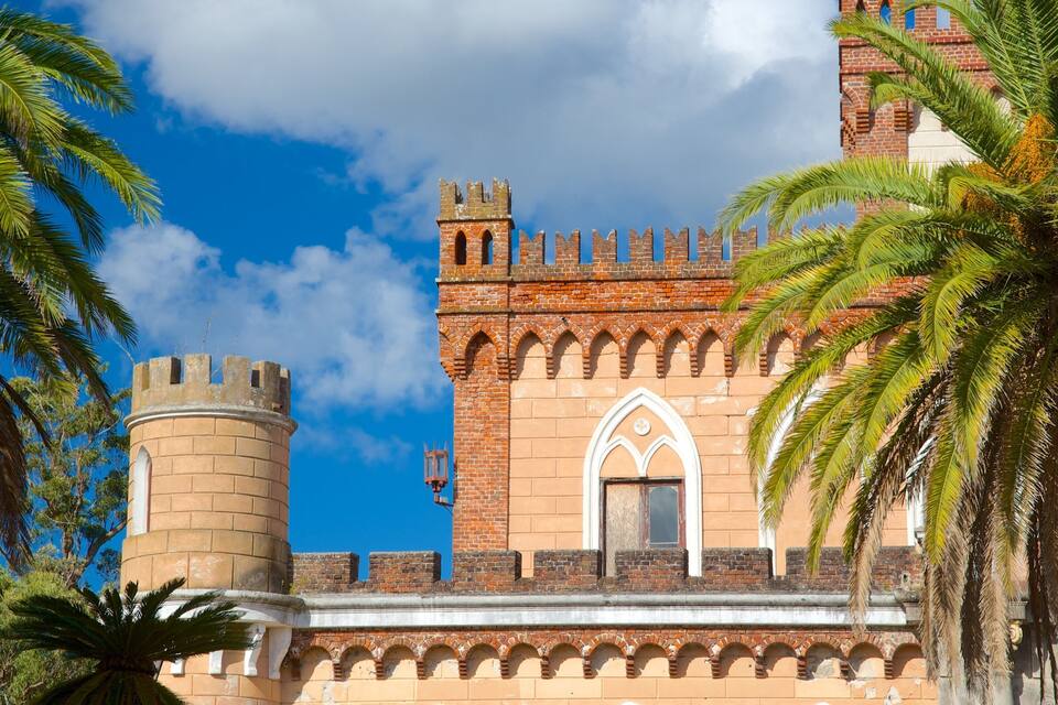 Um edifício histórico com uma torre, janelas em arco e uma parede com ameias.