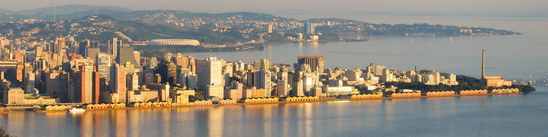 Paisagem costeira com um horizonte imponente, uma grande massa d'água e colinas ao longe.