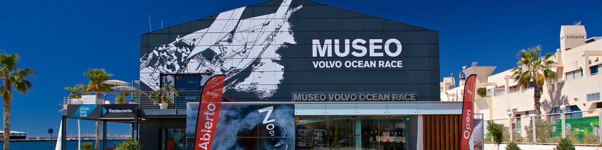 Um edifício com um grande mural de um veleiro e o texto "MUSEO VOLVO OCEAN RACE".