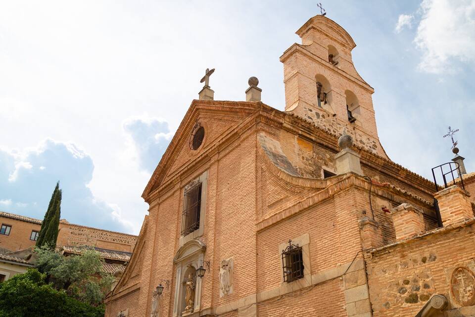 Uma igreja histórica com uma torre de sino e estátuas.