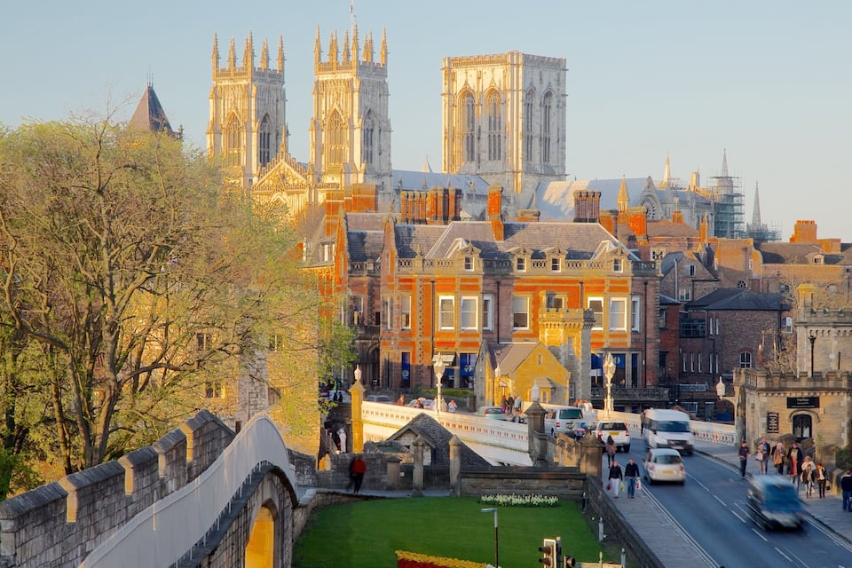 Paisagem urbana histórica com uma catedral imponente, uma ponte e uma mistura de edifícios tradicionais e modernos.