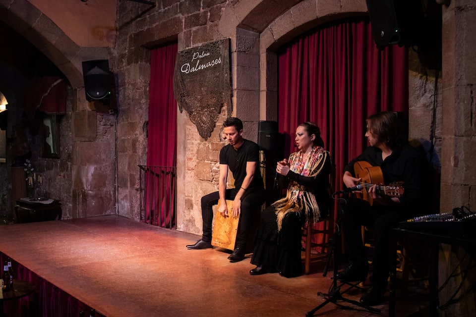 Um palco com cortina vermelha, um letreiro com a inscrição 'Palau Dalmases' e um suporte de microfone.