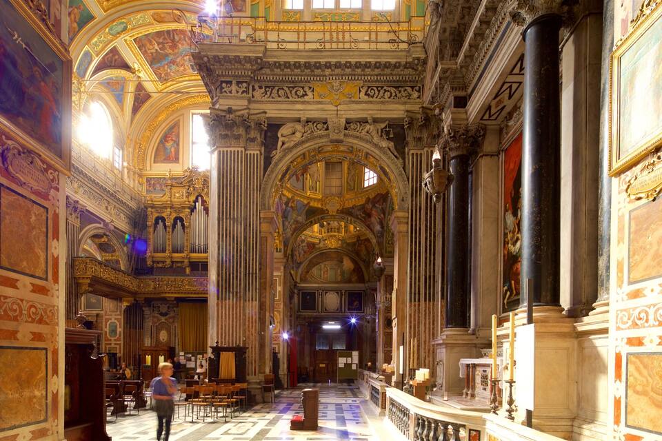 Interior de igreja ornamentado, com tetos altos, frescos detalhados e colunas clássicas.