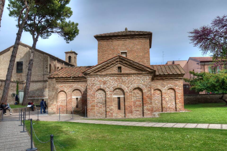 Um edifício histórico de tijolos com janelas em arco e um campanário.