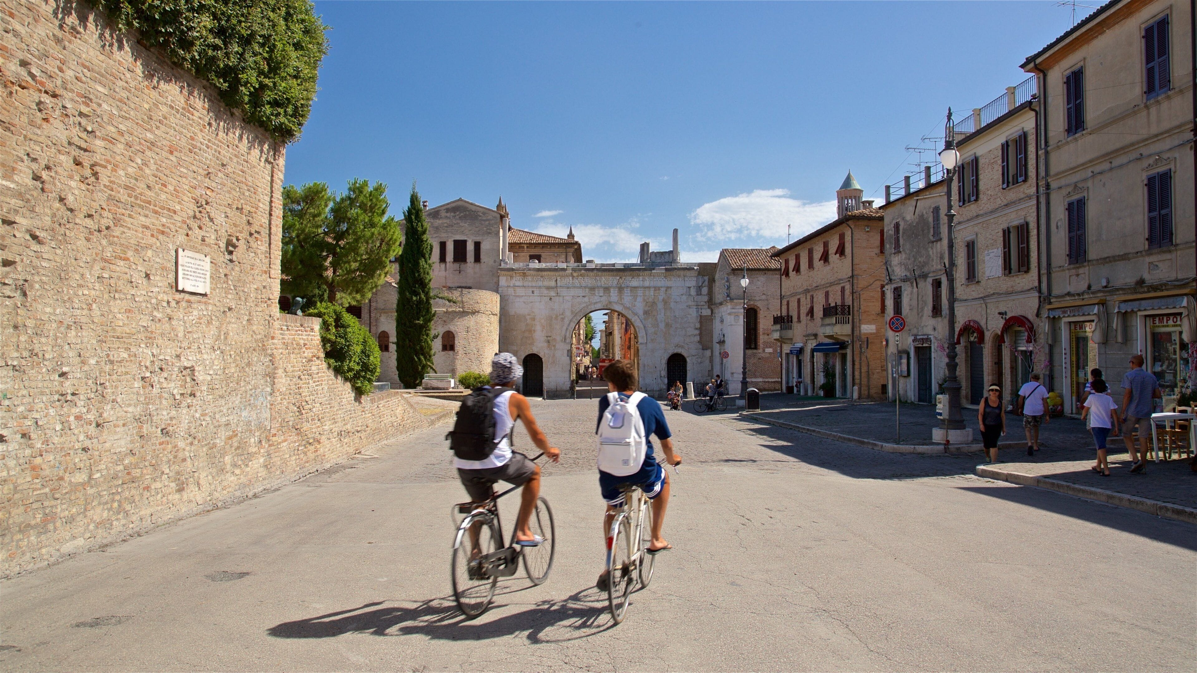 Uma rua histórica com ciclistas, paredes de pedra e edifícios tradicionais.