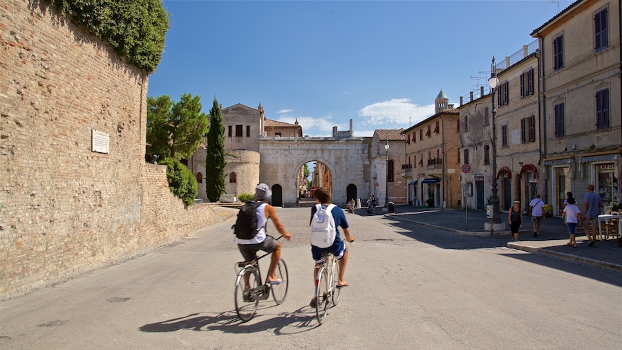 Uma rua histórica com ciclistas, paredes de pedra e edifícios tradicionais.