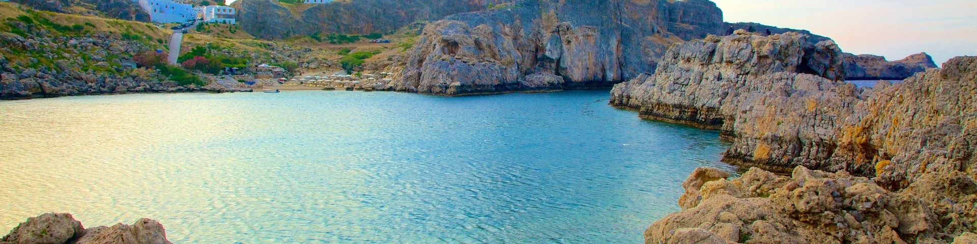 Uma vila costeira com um penhasco rochoso imponente e águas azul-claras.