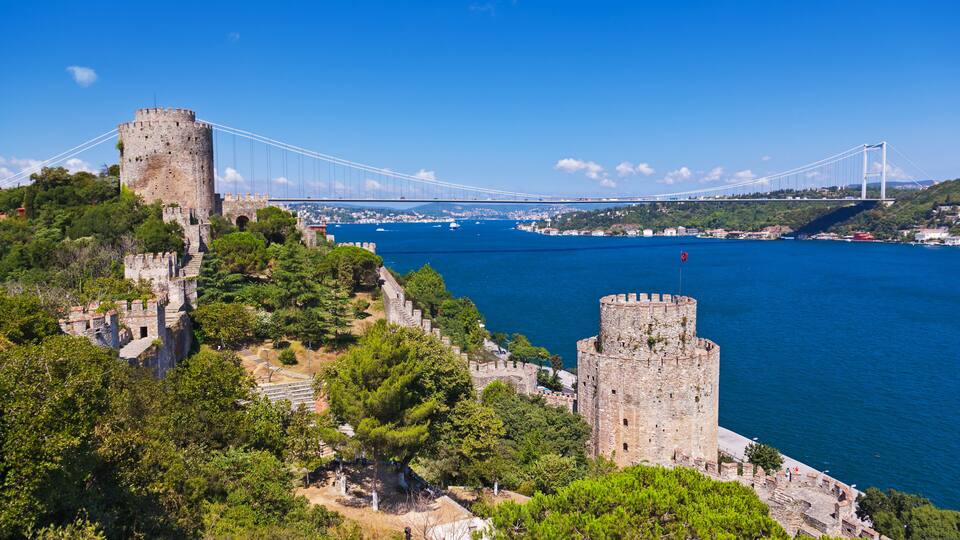 Um castelo à beira-mar com vista para uma ponte e o mar.