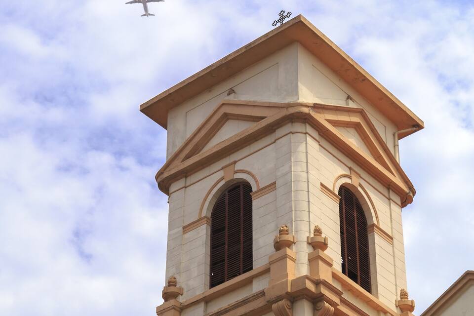 Um edifício histórico com uma torre do relógio, sob um céu parcialmente nublado.
