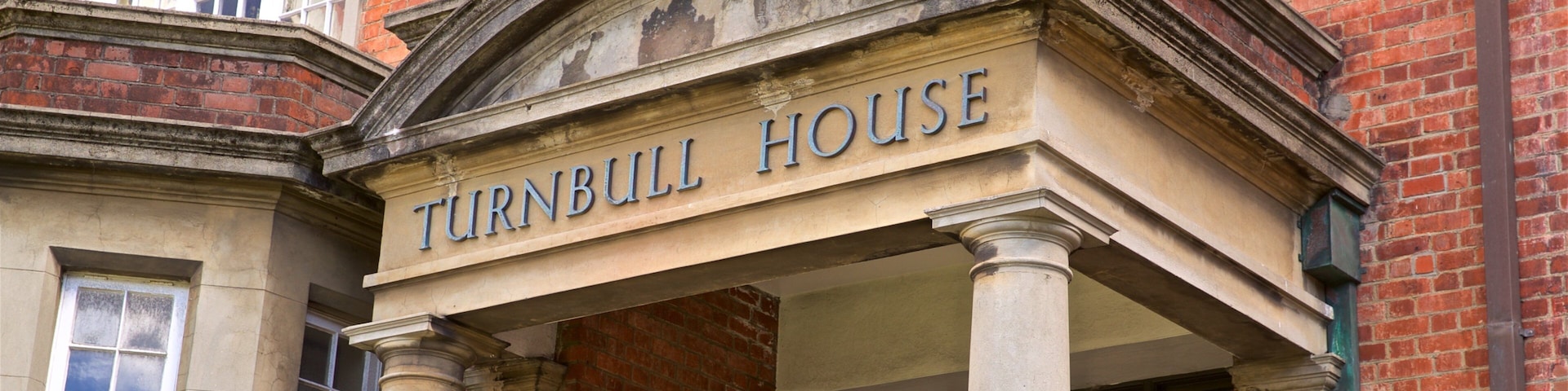 Um edifício com uma placa que diz "TURNBILL HOUSE" sobre um conjunto de colunas.