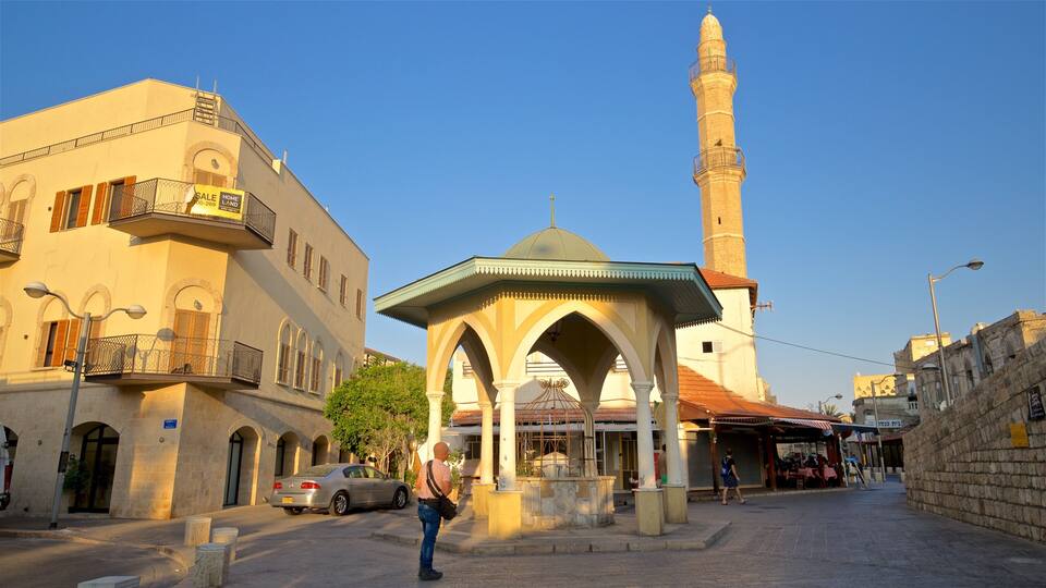 Rua com uma mesquita, um minarete e um pavilhão coberto.