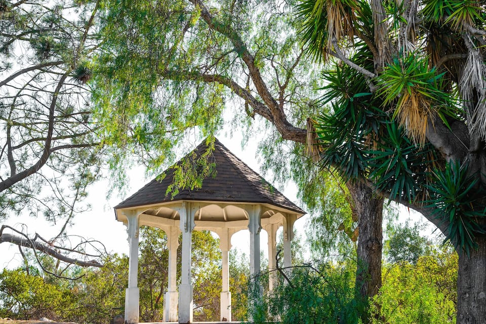 Um gazebo rodeado por vegetação exuberante e árvores.