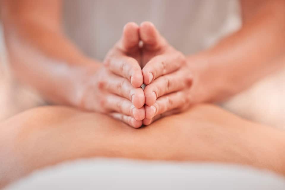 Mãos em posição de oração sobre uma superfície branca.