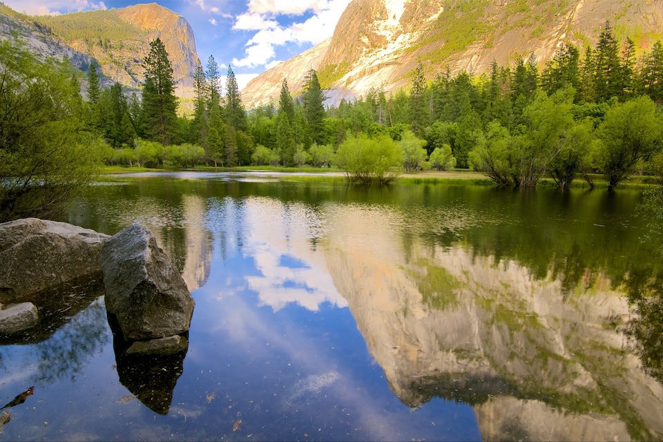 Um rio calmo refletindo árvores e montanhas.