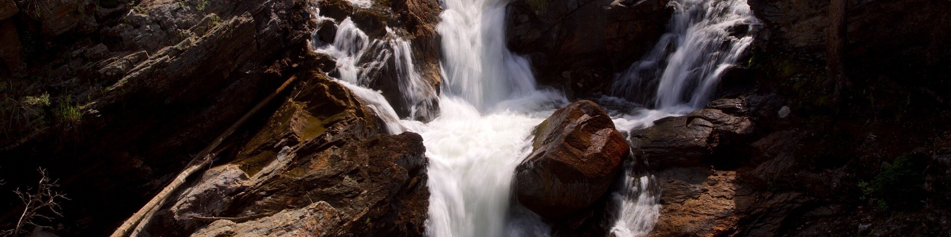 Uma cascata desce pelas rochas em uma área arborizada.