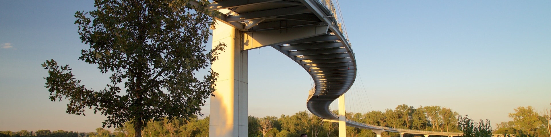 Bob Kerrey Pedestrian Bridge caracterizando um pôr do sol, um rio ou córrego e um parque