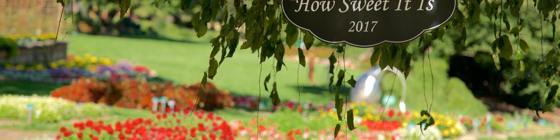 Placa de jardim com a inscrição 'How Sweet It Is' e a data de 2017.