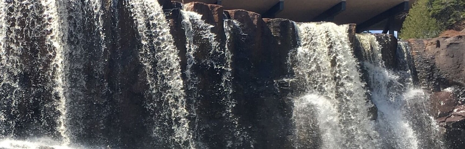 Uma cascata em vários níveis com uma ponte sobre ela.