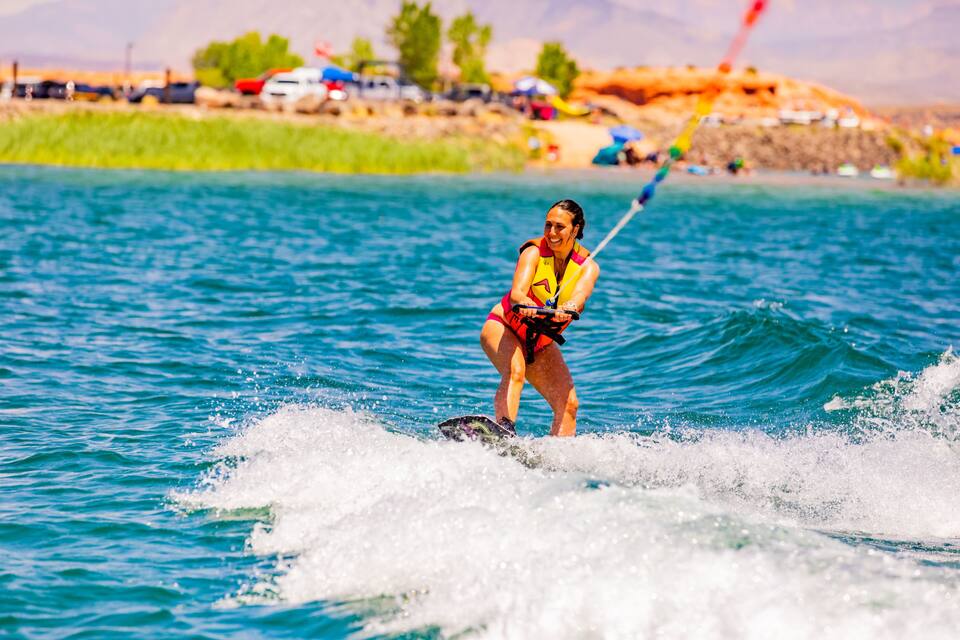 Uma pessoa praticando wakeboard em um lago, com montanhas ao fundo.