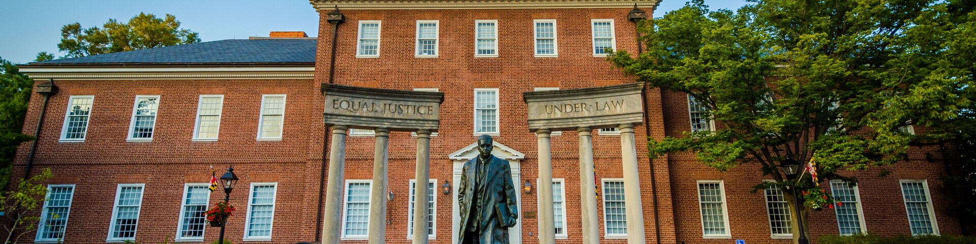 Um edifício de tijolos com colunas, uma estátua e a inscrição 'EQUAL JUSTICE UNDER LAW' na fachada.