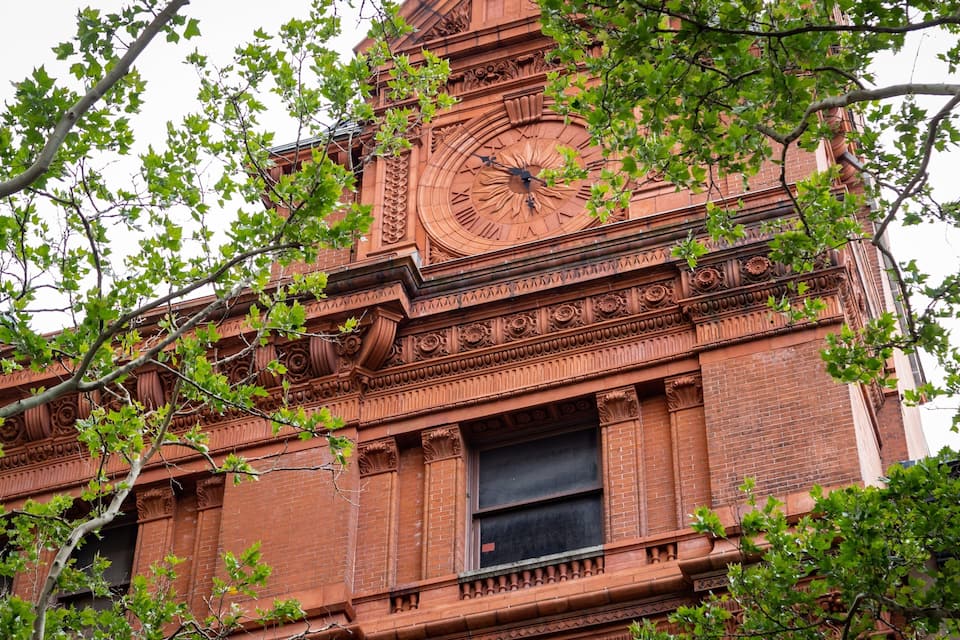 Um edifício histórico com intrincado trabalho em tijolo e um grande relógio.