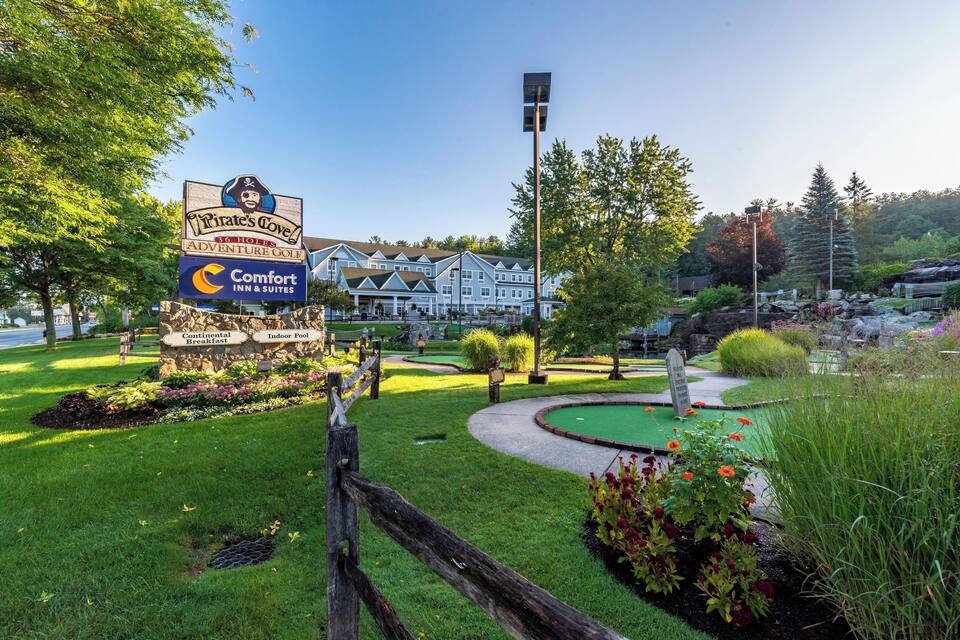 Um campo de golfe com uma placa a indicar 'Pirate's Cove Adventure Golf' e 'Comfort Inn & Suites'.