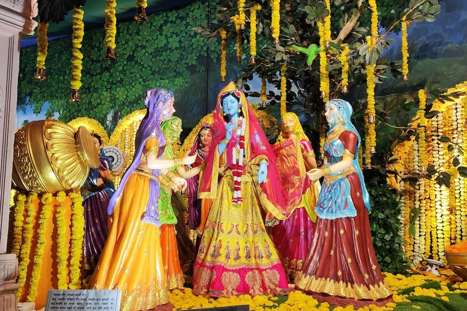Um templo com estátuas de divindades em vestes coloridas, cercado por flores e elementos decorativos.
