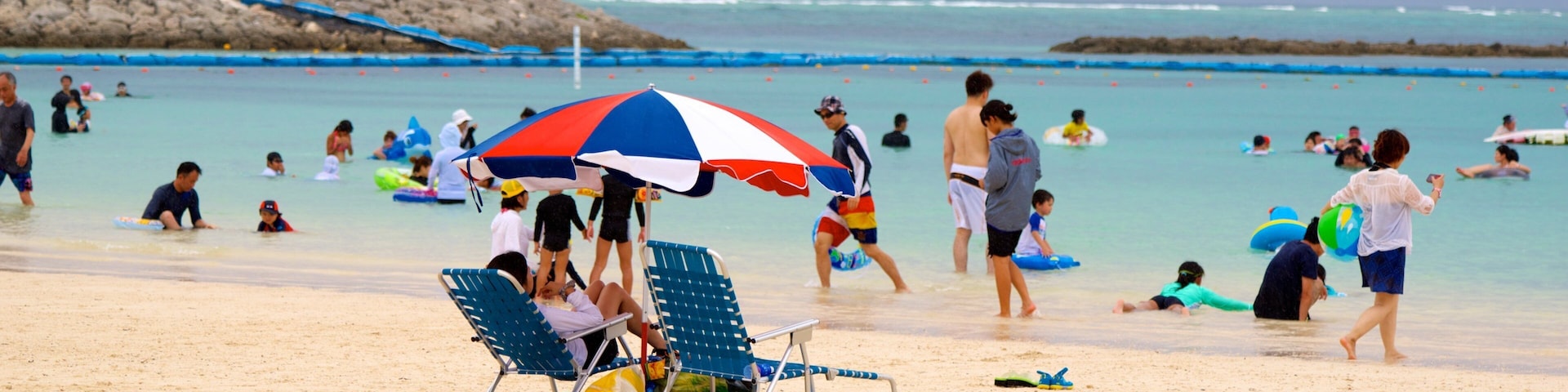 Okinawa mostrando uma praia de areia assim como um grande grupo de pessoas