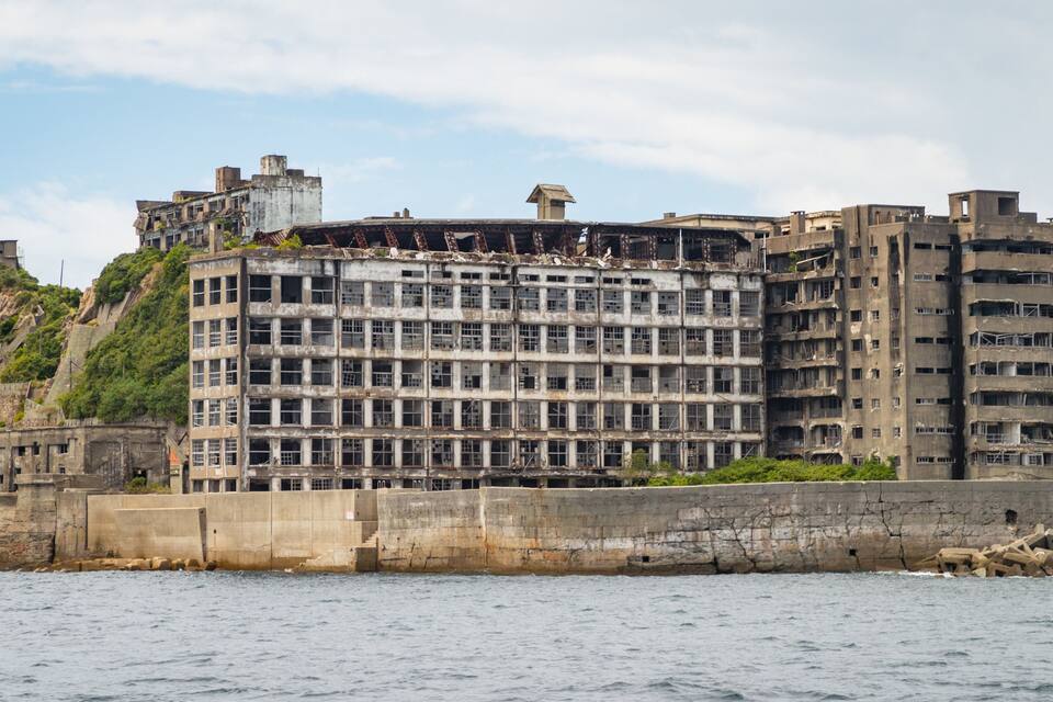 Um edifício grande e de vários andares com fachada desgastada, localizado à beira da água.