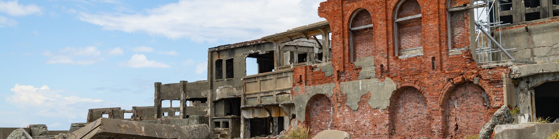 Um edifício de tijolos em ruínas, com janelas em arco e uma parte desabada.