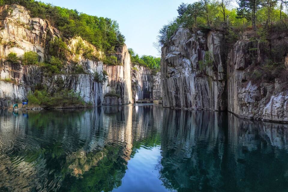Um rio calmo refletindo penhascos e árvores ao redor.