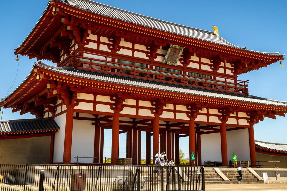 Uma pagoda japonesa tradicional com vários níveis, vigas de madeira vermelhas e telhado telhado.