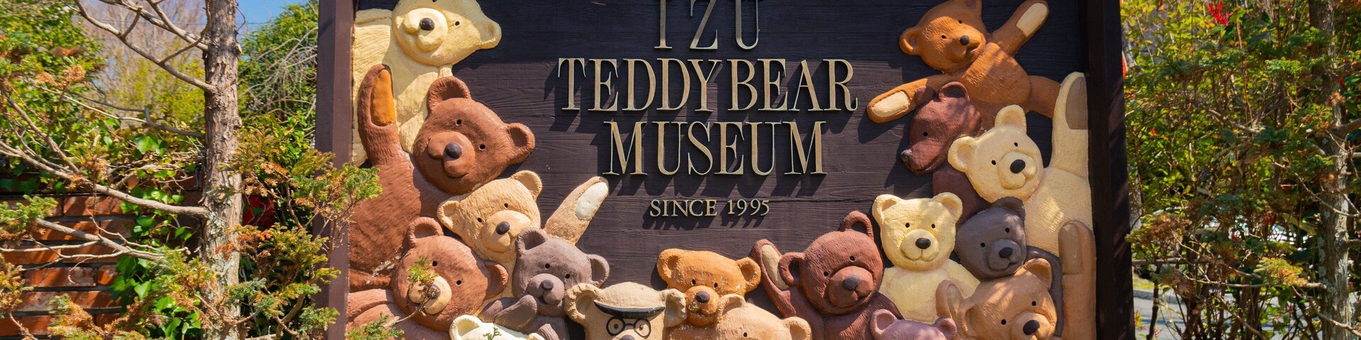 Placa para o Museu dos Ursos de Pelúcia de Izu, com diversos ursos de pelúcia em exposição.