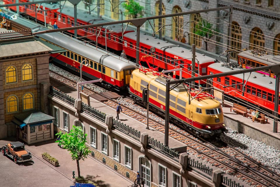Um modelo detalhado de uma estação de trem com várias linhas, trens e prédios em miniatura.