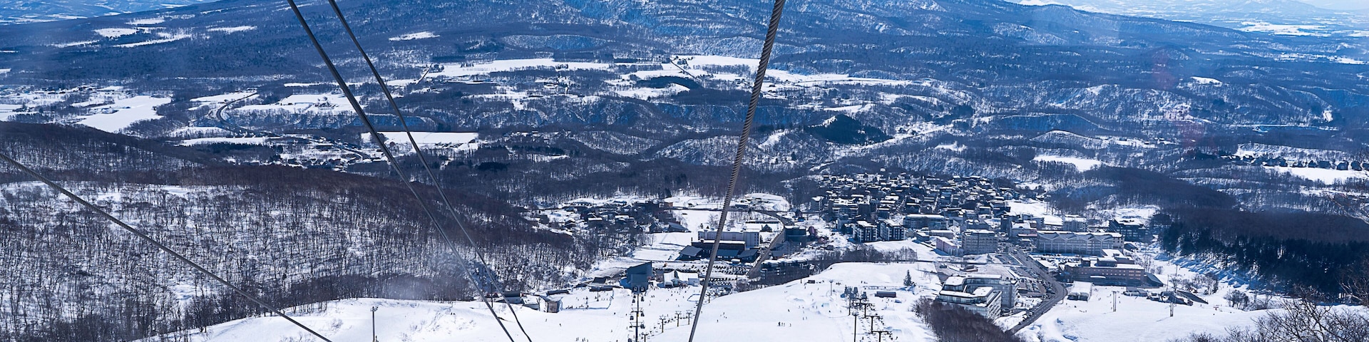Montanha coberta de neve com um teleférico em primeiro plano.