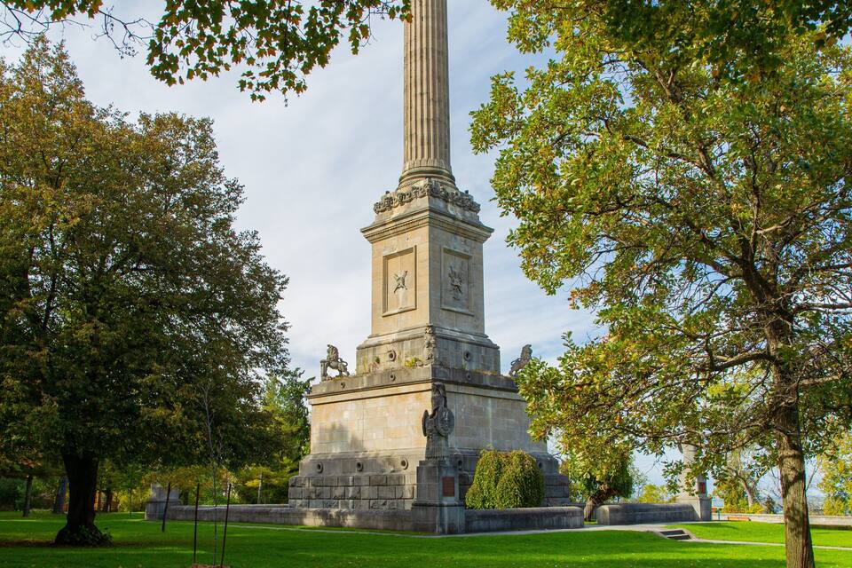 Um monumento alto cercado por árvores e grama.