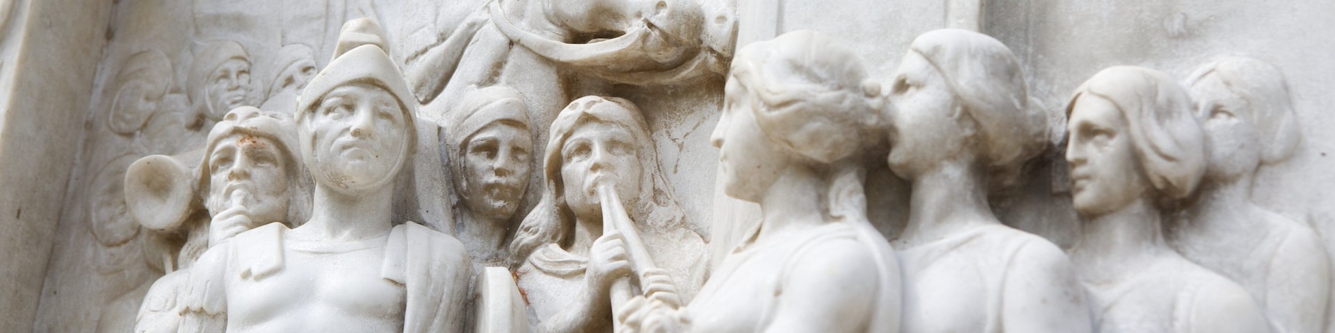 Escultura em pedra detalhada em baixo-relevo retratando uma cena histórica com figuras trajadas em estilo clássico.