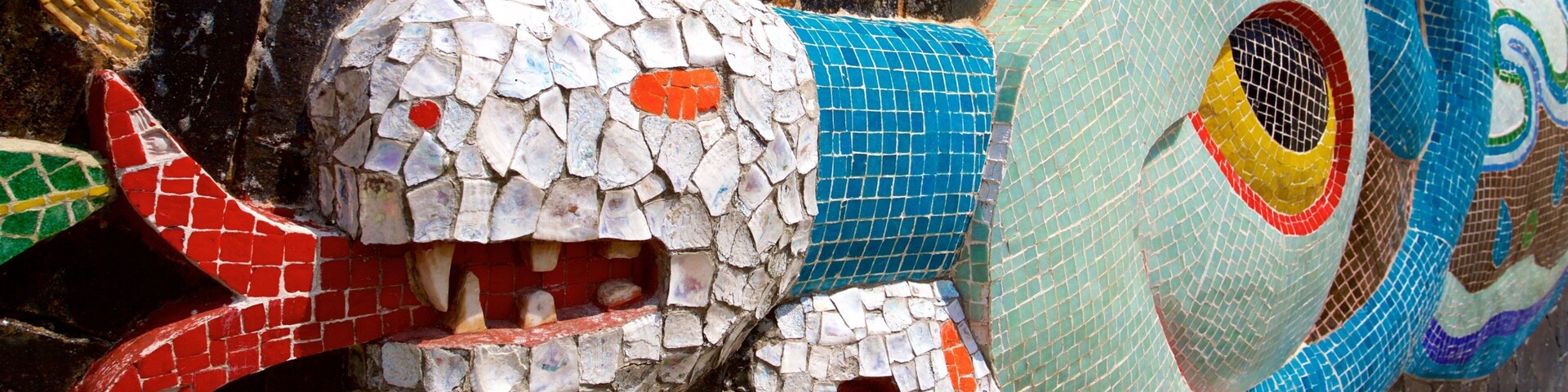 Uma escultura em mosaico de um peixe com boca vermelha e nadadeiras azuis.