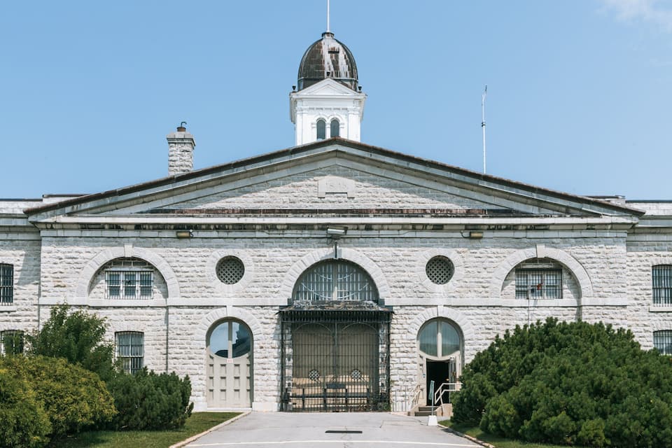 Um amplo edifício de pedra branca com uma cúpula central, janelas em arco e um mastro.
