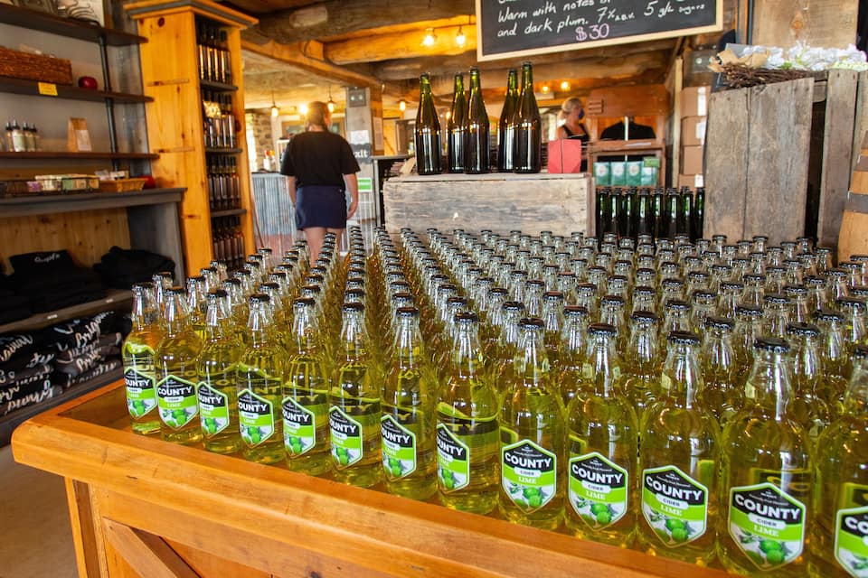 Uma mesa de madeira repleta de garrafas de County Cider Lime.
