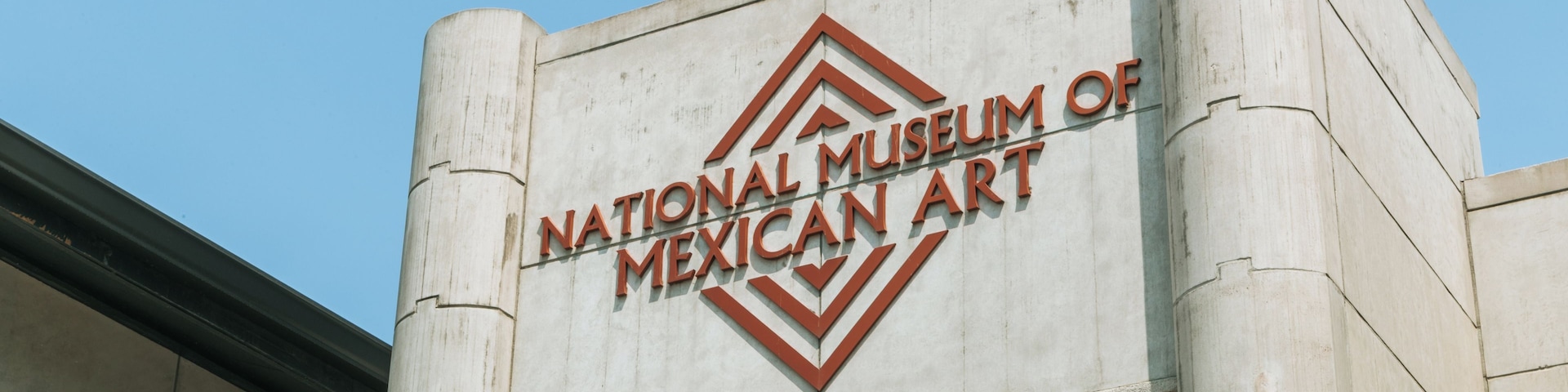 Exterior do Museu Nacional de Arte Mexicana, com seu logotipo geométrico característico e colunas de concreto.