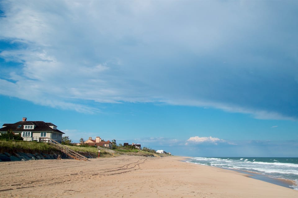 Uma praia com uma casa e céu claro.