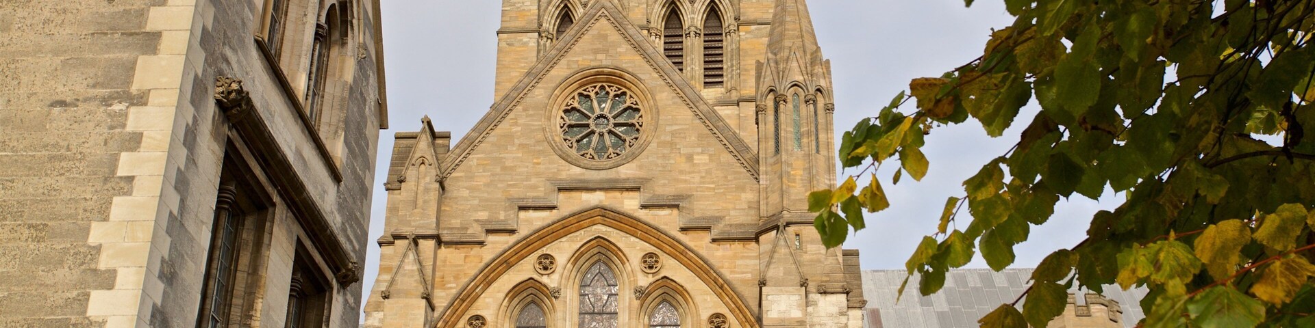Uma igreja histórica com uma torre alta, janelas em arco grandes e detalhada talha em pedra.